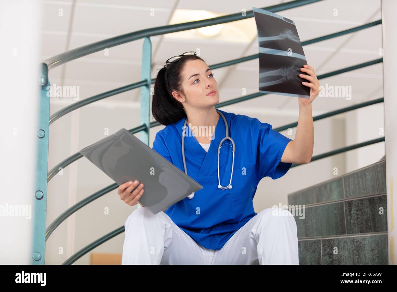 female doctor sitting in stairs looking at x rays Stock Photo - Alamy