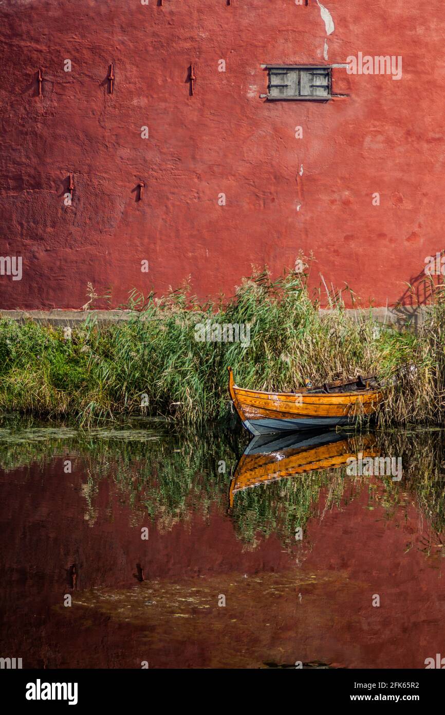 Walls of Malmo Castle and a small boat reflecting in a moat, Sweden ...