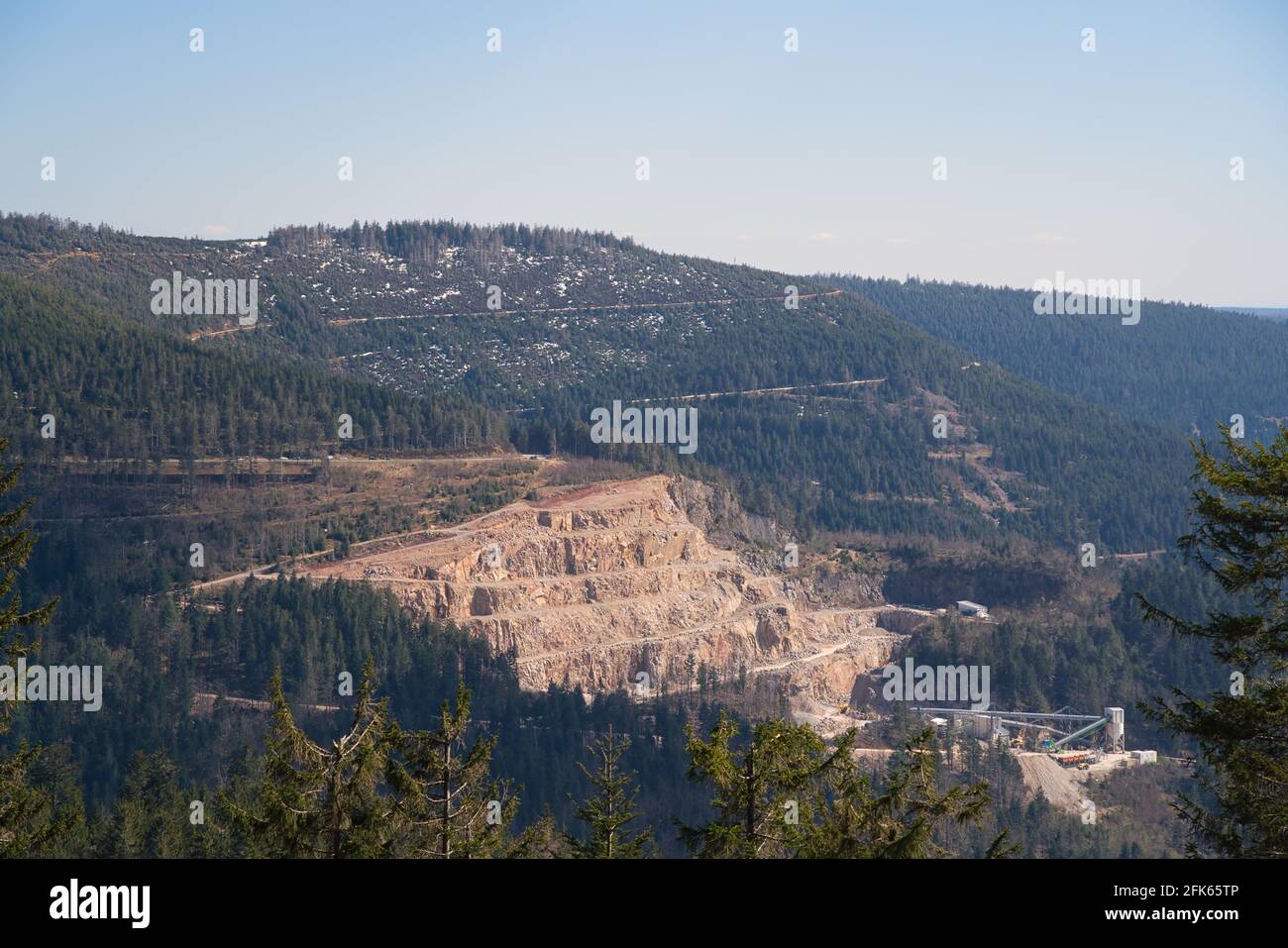 Landscape of a quarry surrounded by hills covered in greenery under the ...