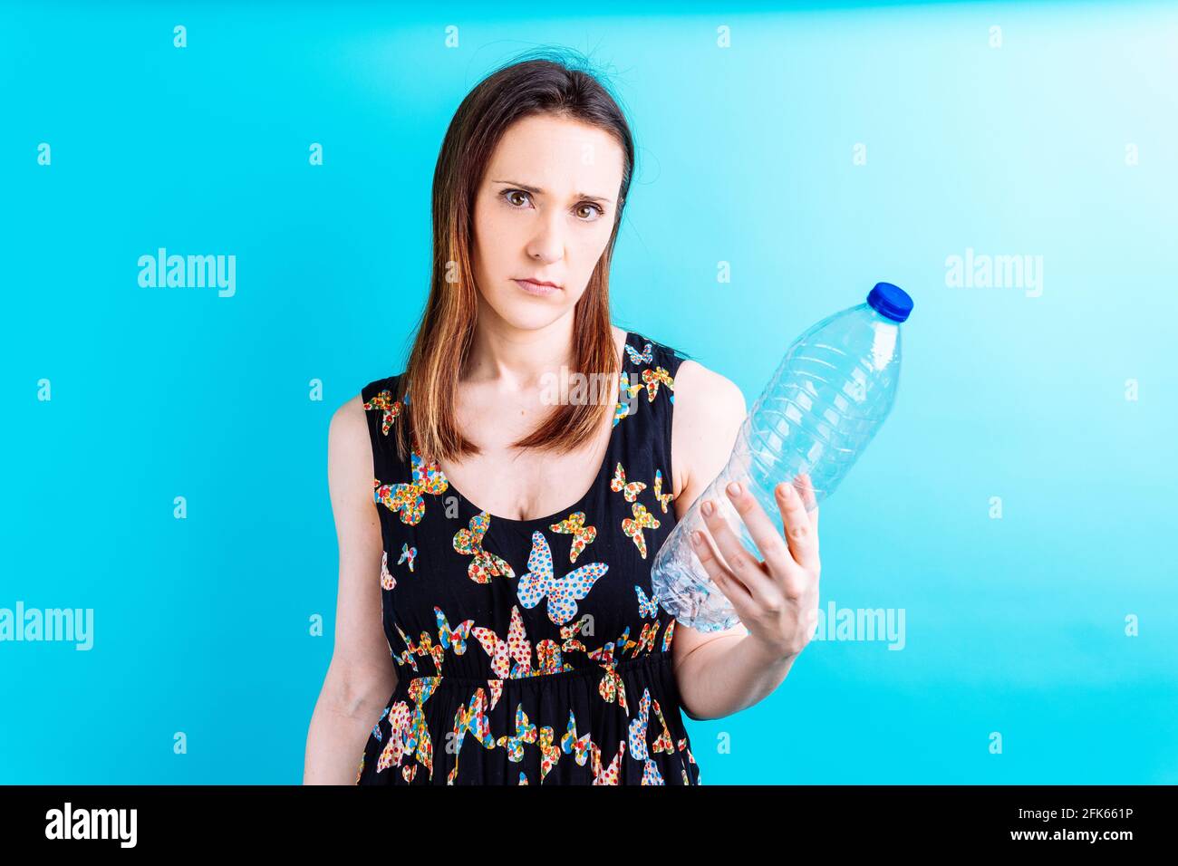 Beautiful young woman with angry ecologist face holding a plastic ...
