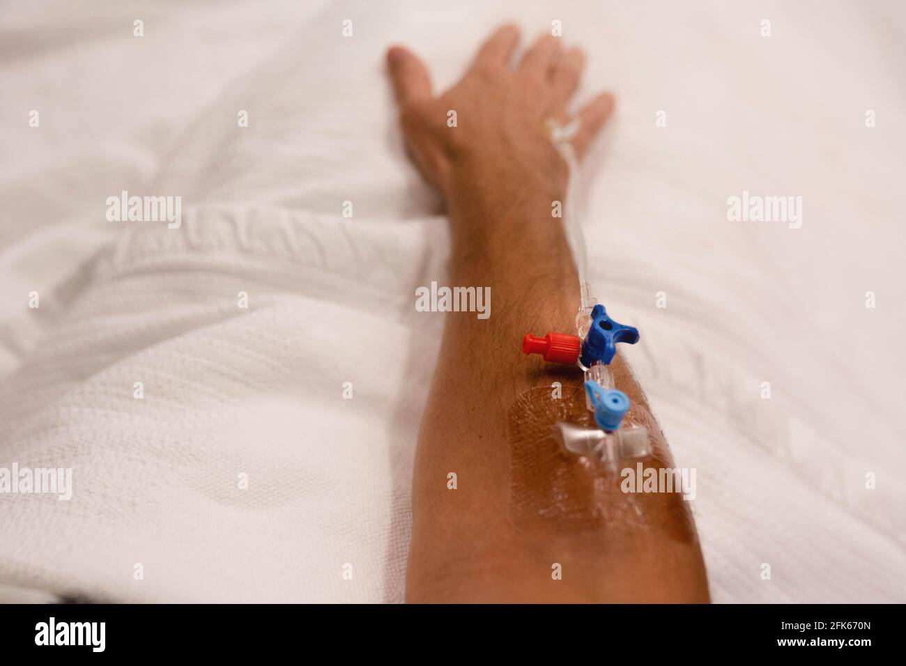 Focus on suffering patient with intravenous therapy lying in hospital ...