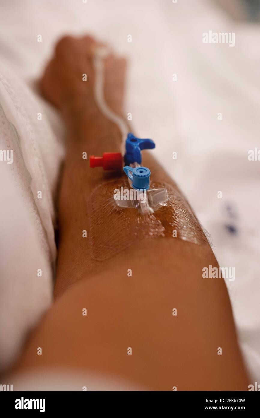 Focus on suffering patient with intravenous therapy lying in hospital ...