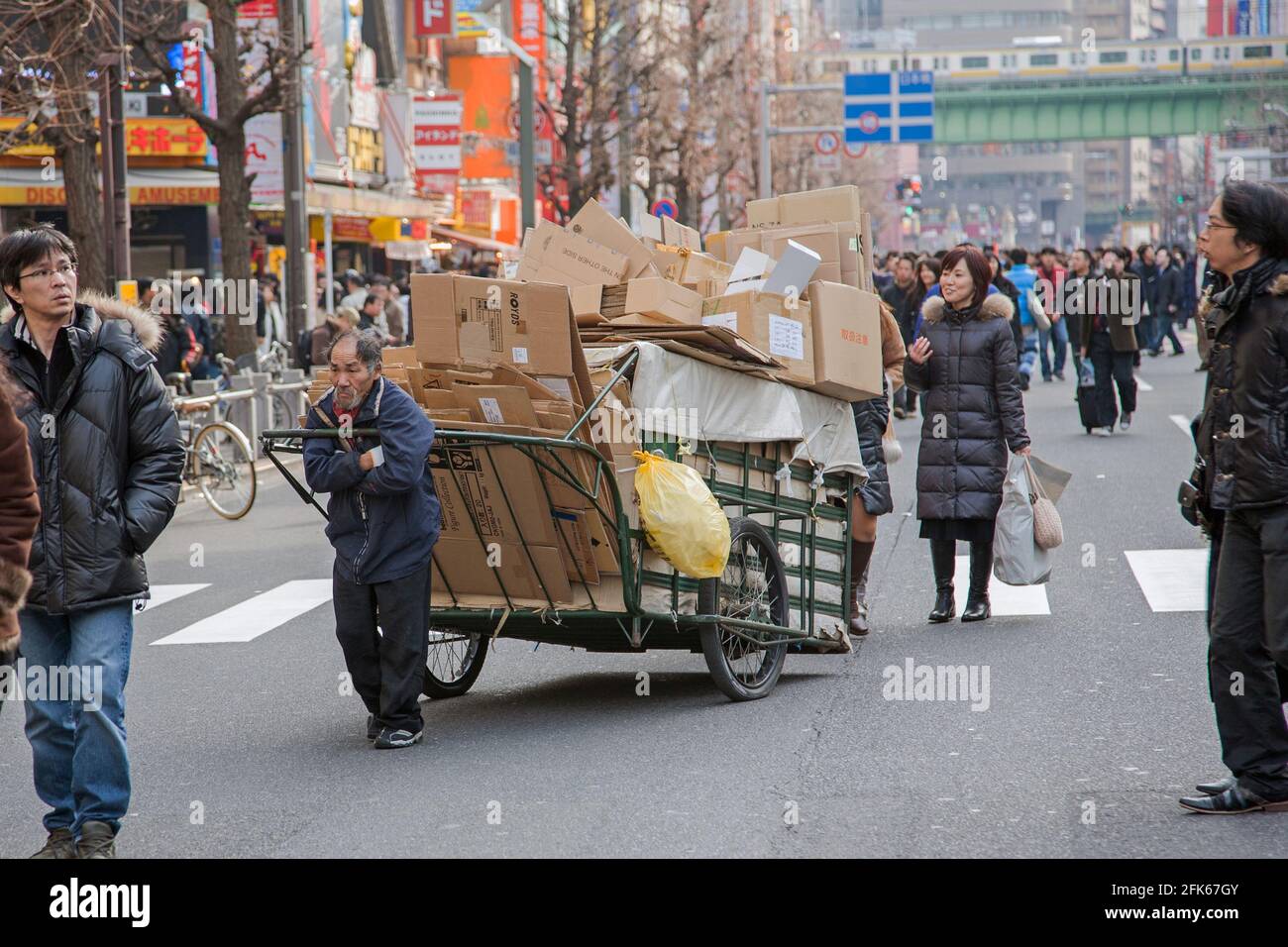 Japanese male pulls heavy cart containing cardboard through ...