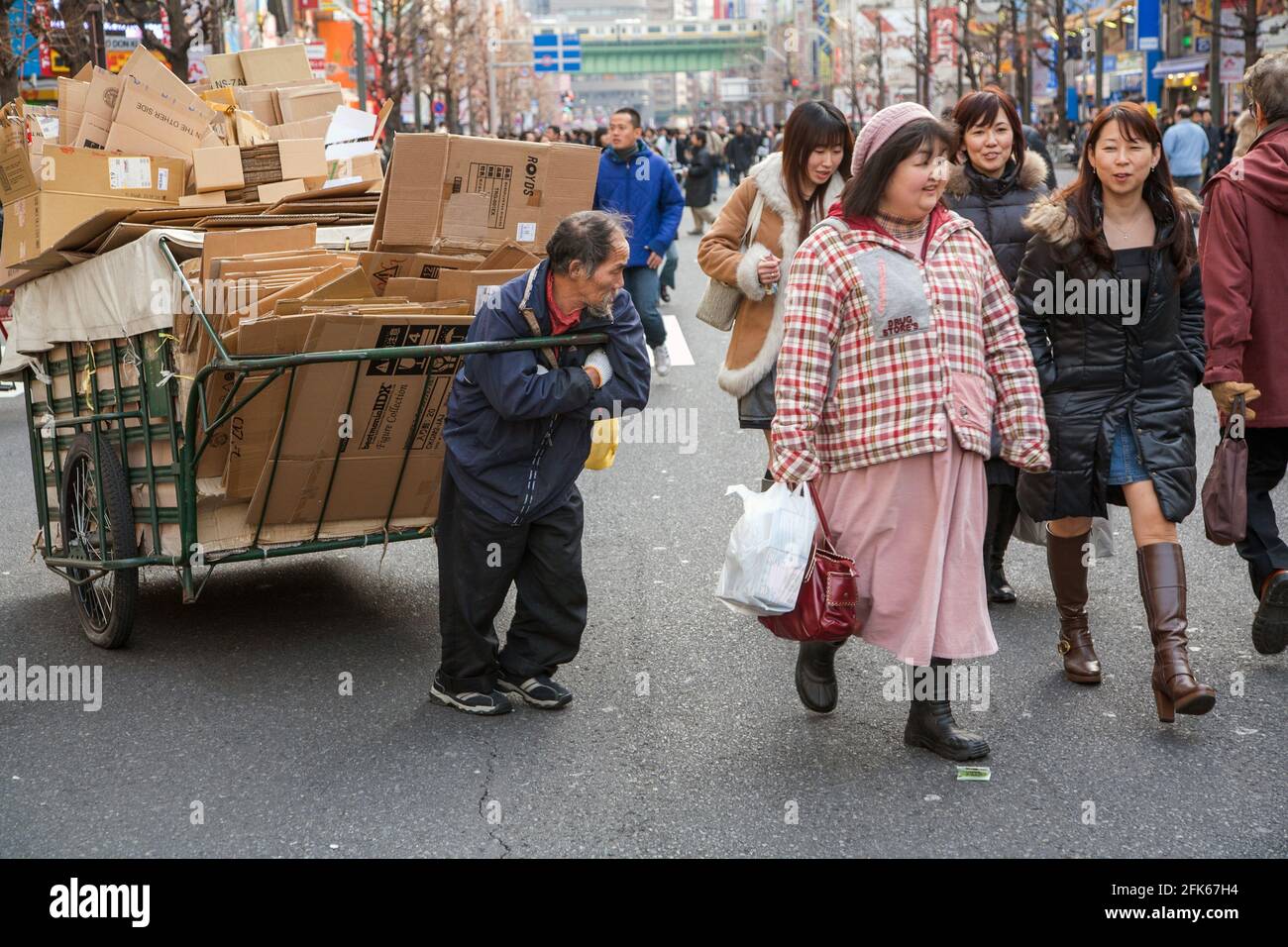 Japanese male pulls heavy cart containing cardboard through ...