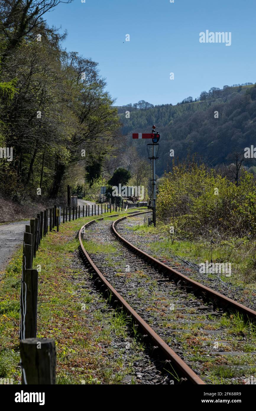 railway tracks on a corner next to a dirt road with a signal to the ...
