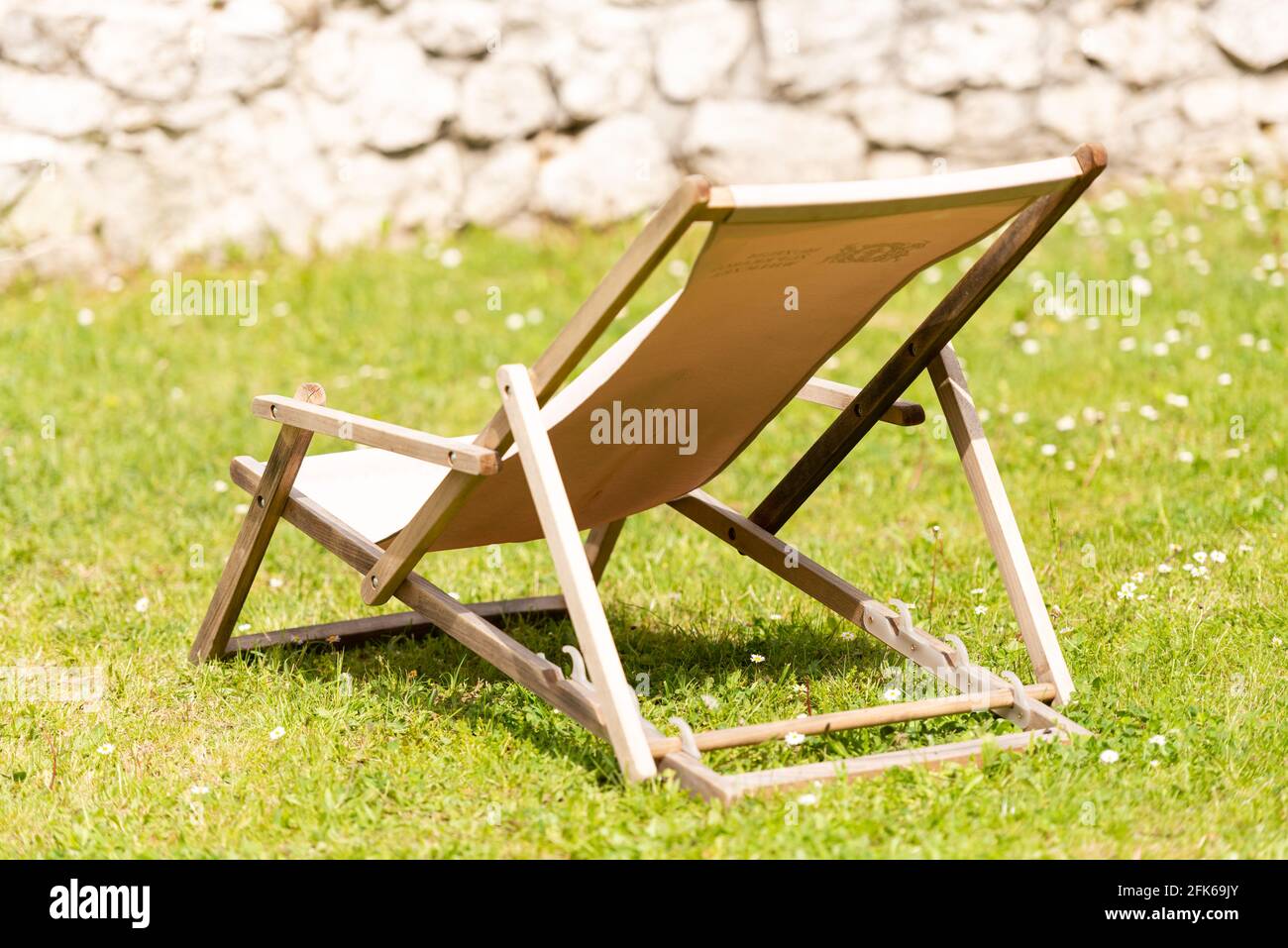 Sun lounger on the grass under the sun. A place for sunbathing. Wooden ...
