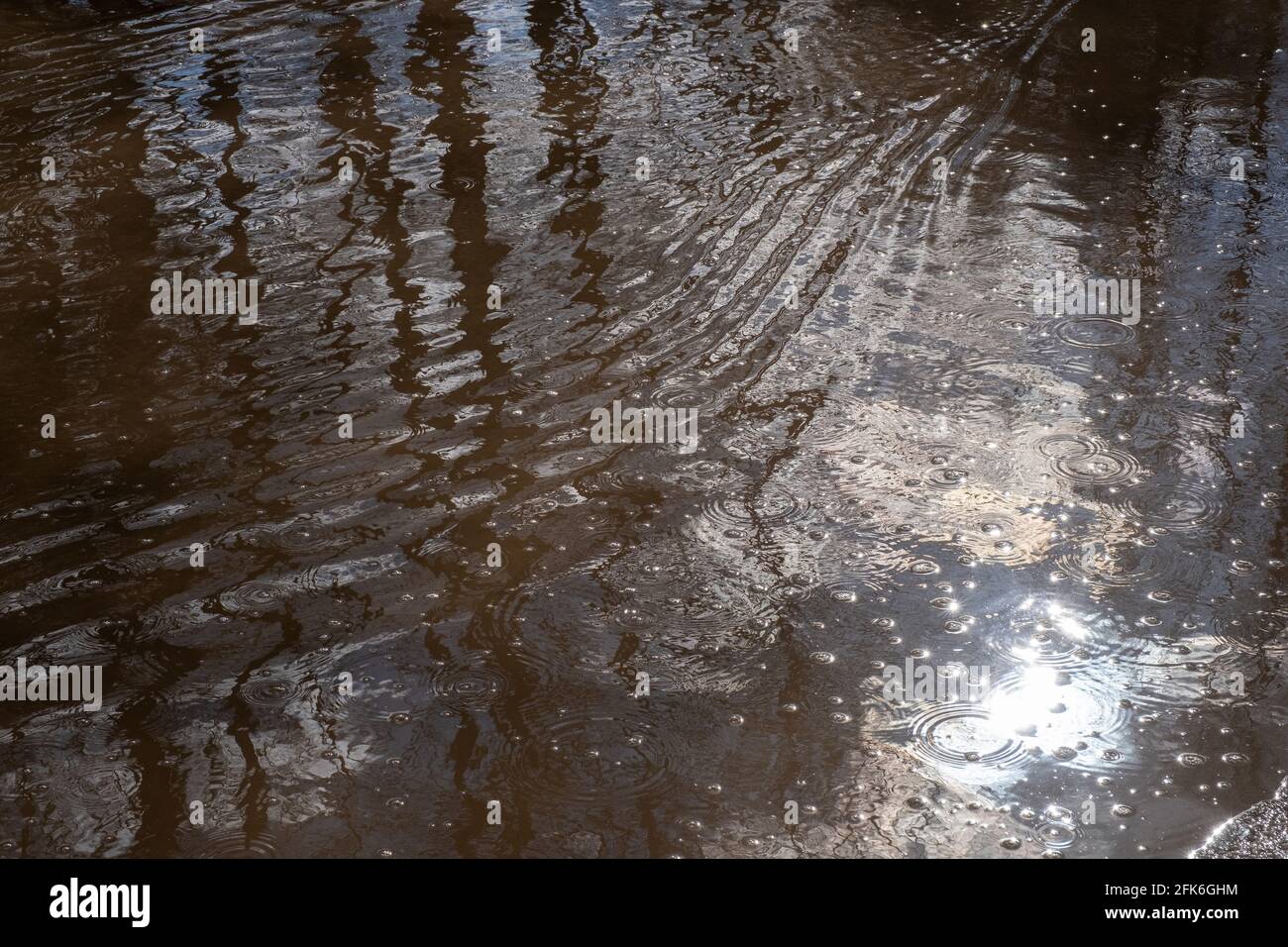Bright sun glare and small waves on a spring puddle. An abstraction ...