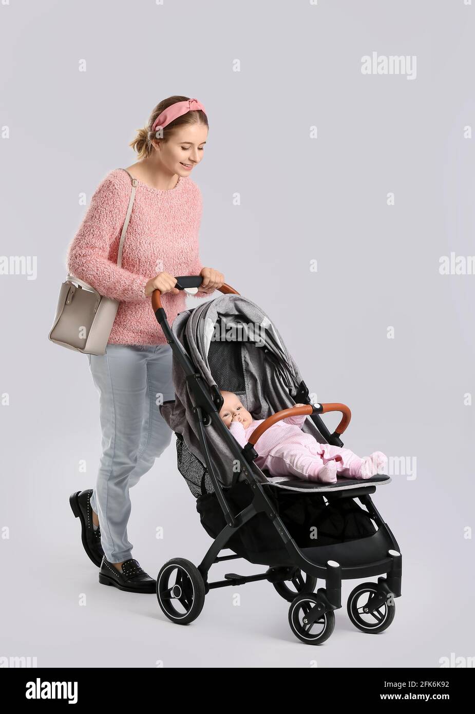 Woman and her cute baby in stroller on white background Stock Photo - Alamy