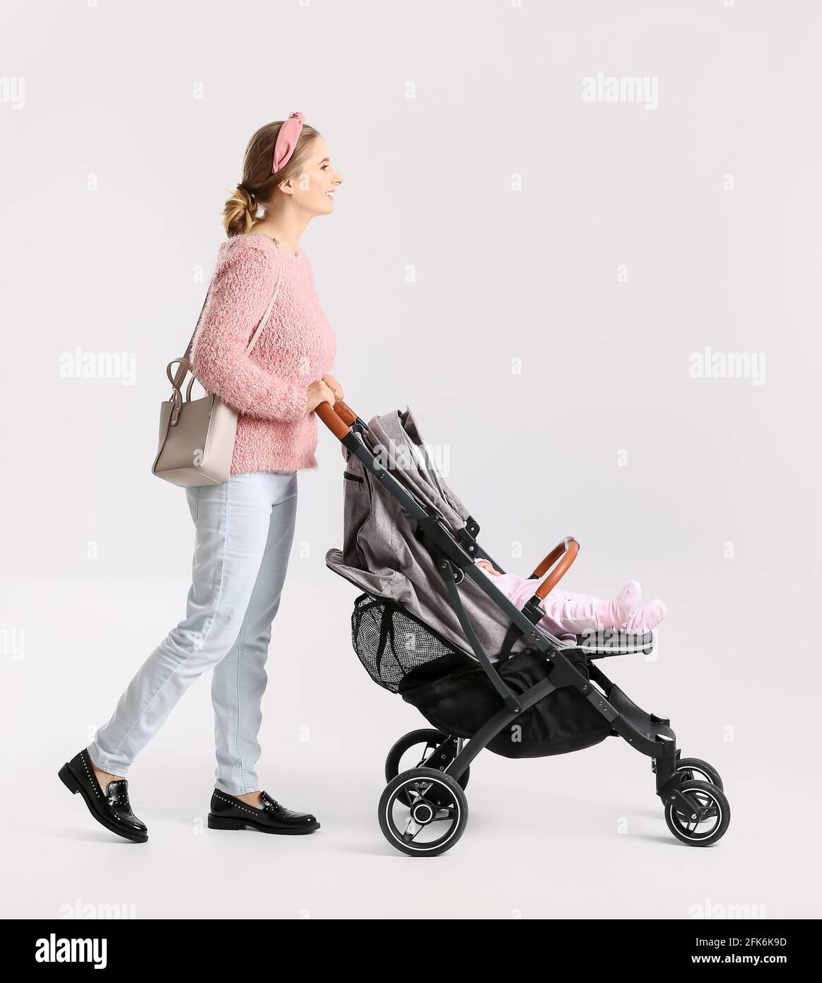 Woman and her cute baby in stroller on white background Stock Photo - Alamy
