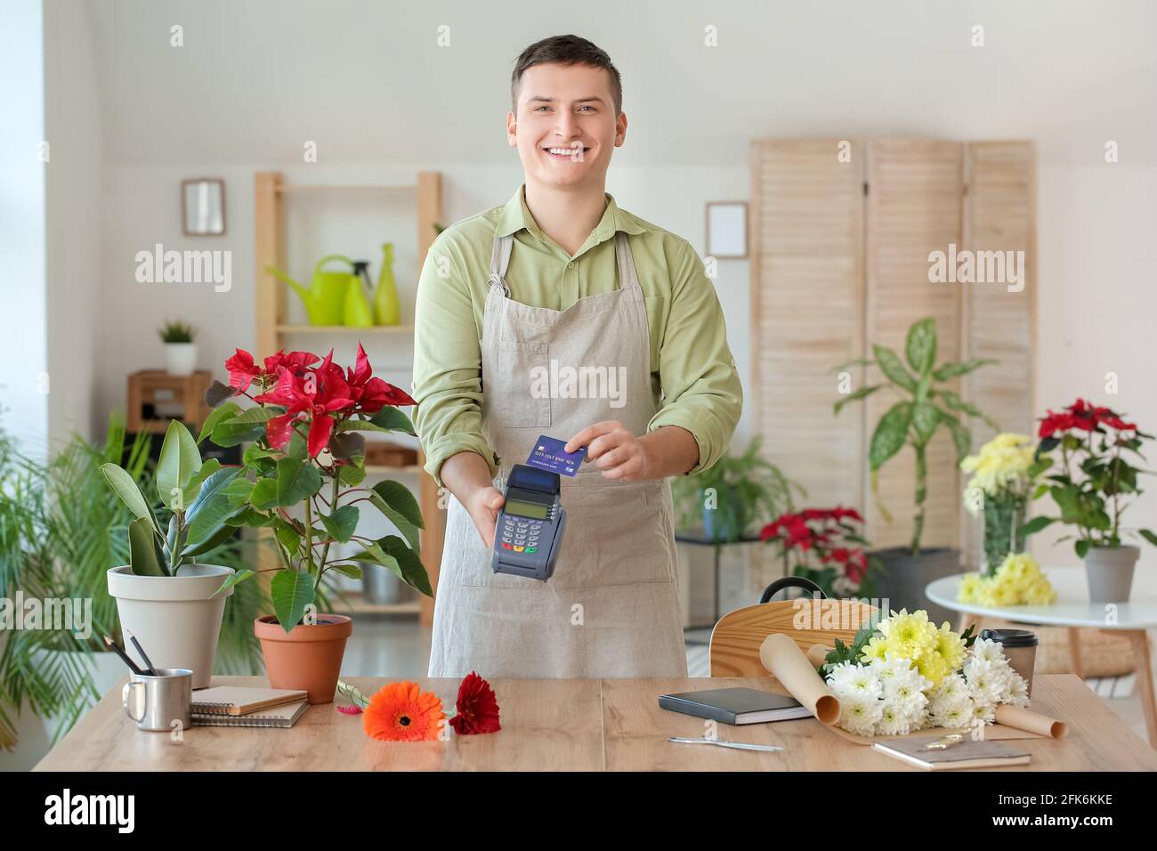 Seller with payment terminal in flower shop Stock Photo - Alamy