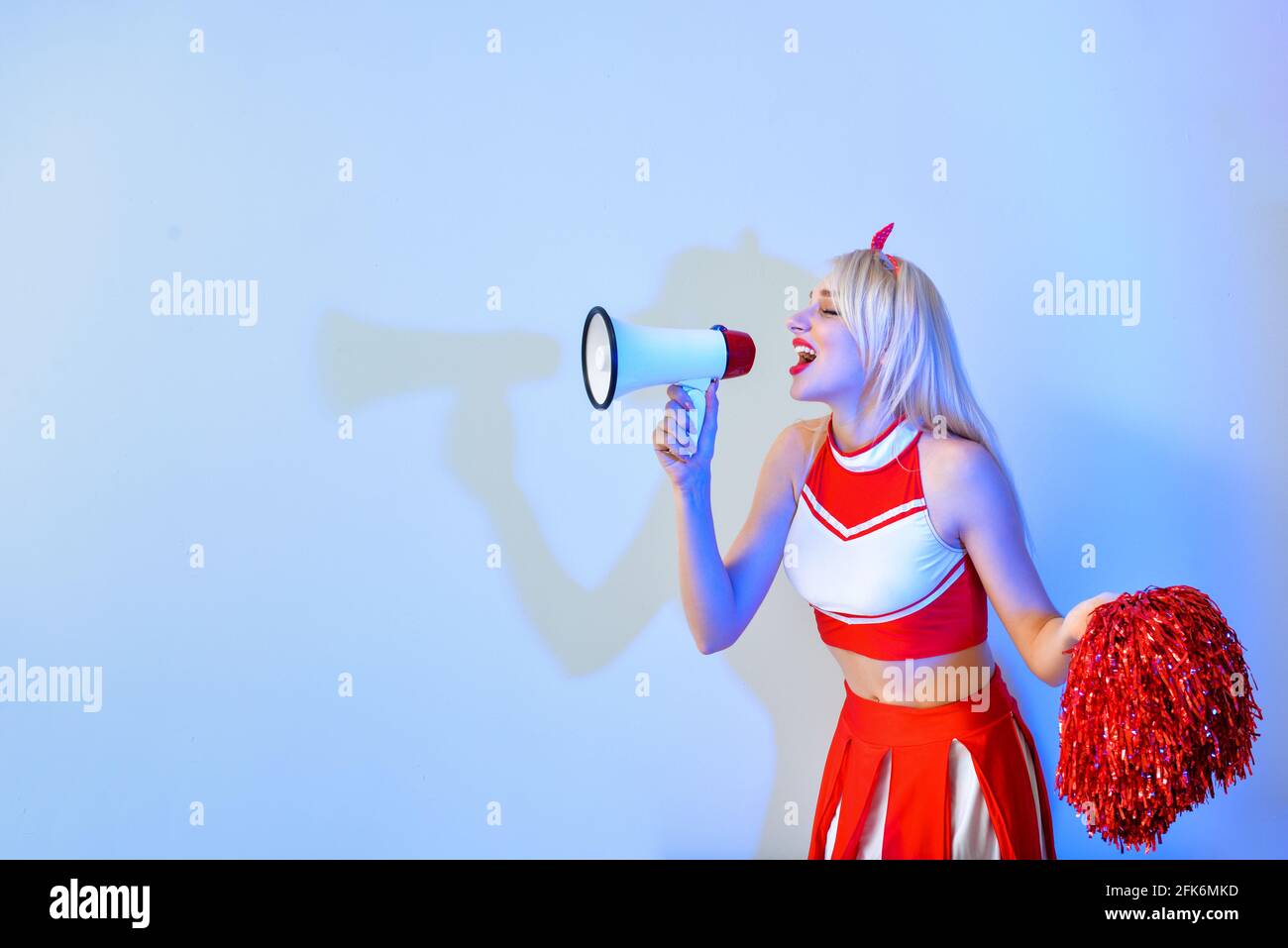 Beautiful cheerleader with megaphone on color background Stock Photo ...