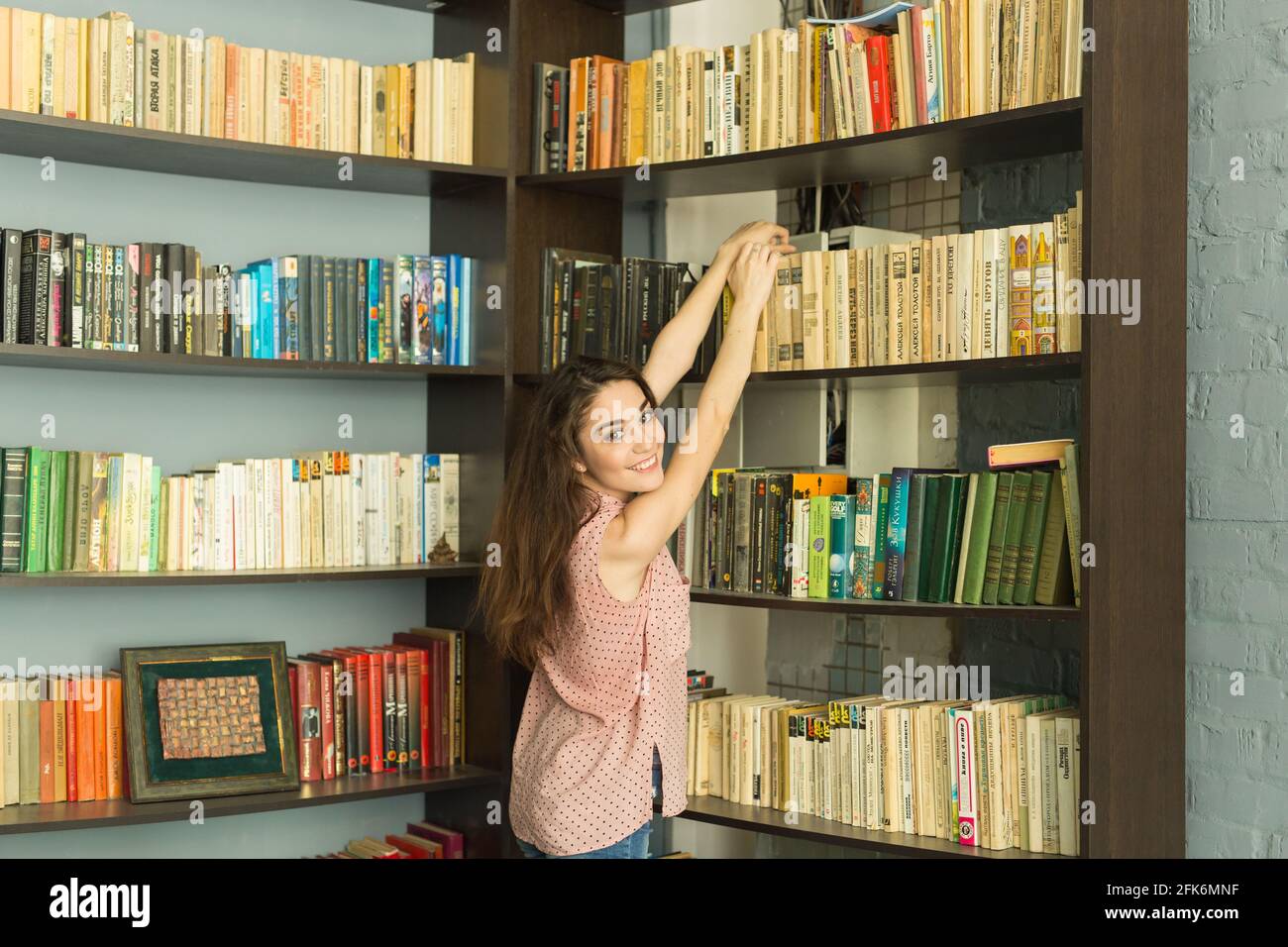 Reading, library and people concept- girl reaching for a book from ...
