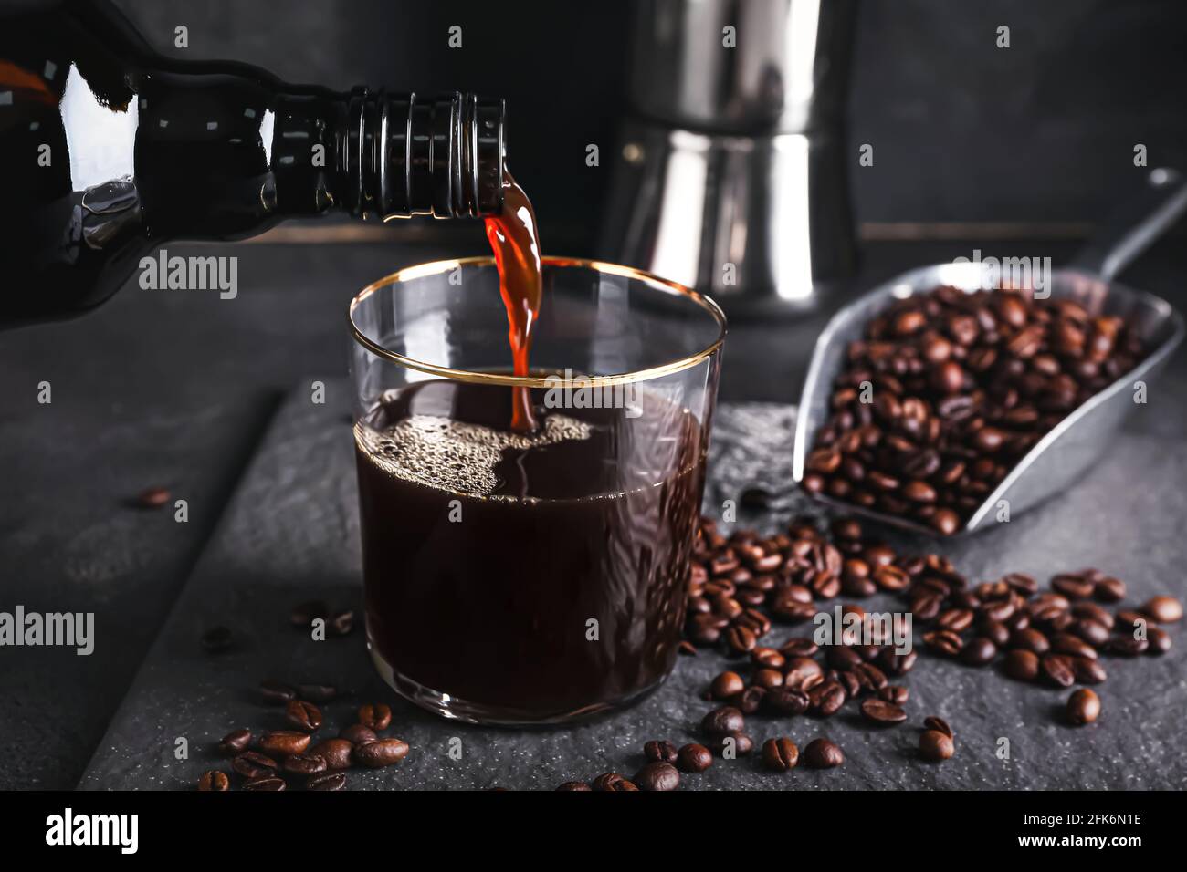 Pouring of tasty cold brew from bottle into glass on dark background ...
