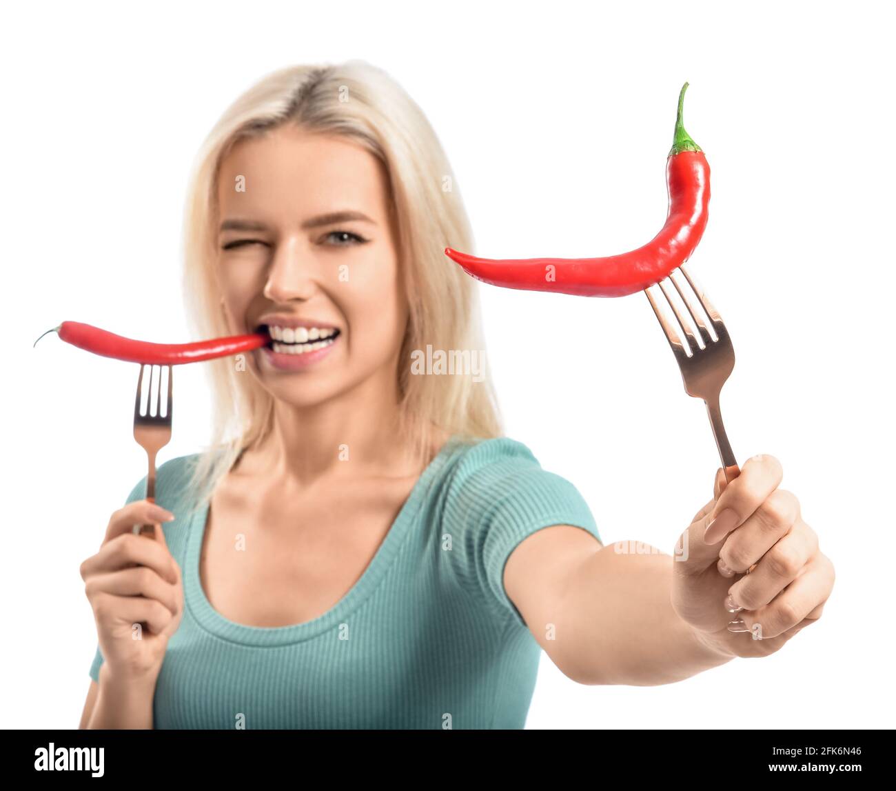 Beautiful young woman eating hot chili peppers on white background ...