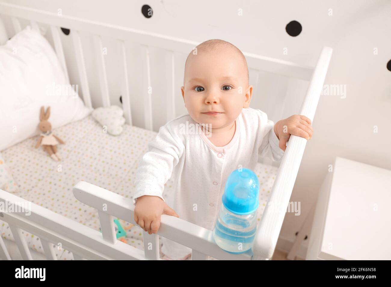 Cute little baby with bottle of water in crib at home Stock Photo - Alamy
