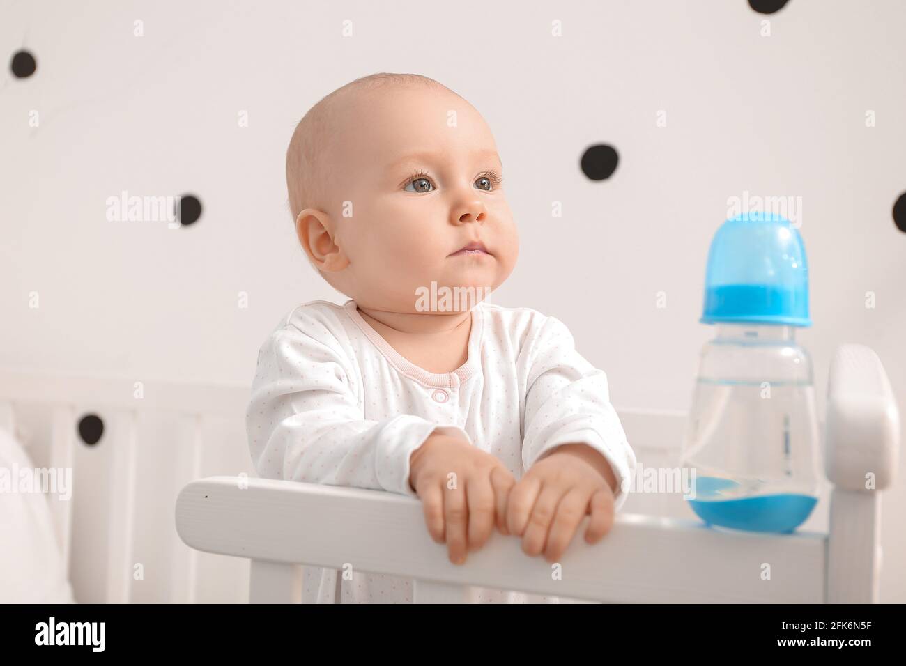 Cute little baby with bottle of water in crib at home Stock Photo - Alamy