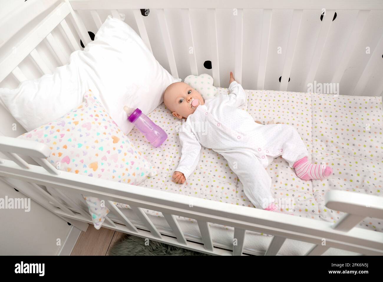 Cute little baby with bottle of water in crib at home Stock Photo - Alamy