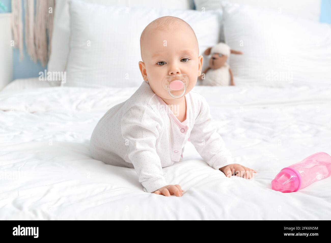 Cute little baby with bottle of water on bed in room Stock Photo - Alamy