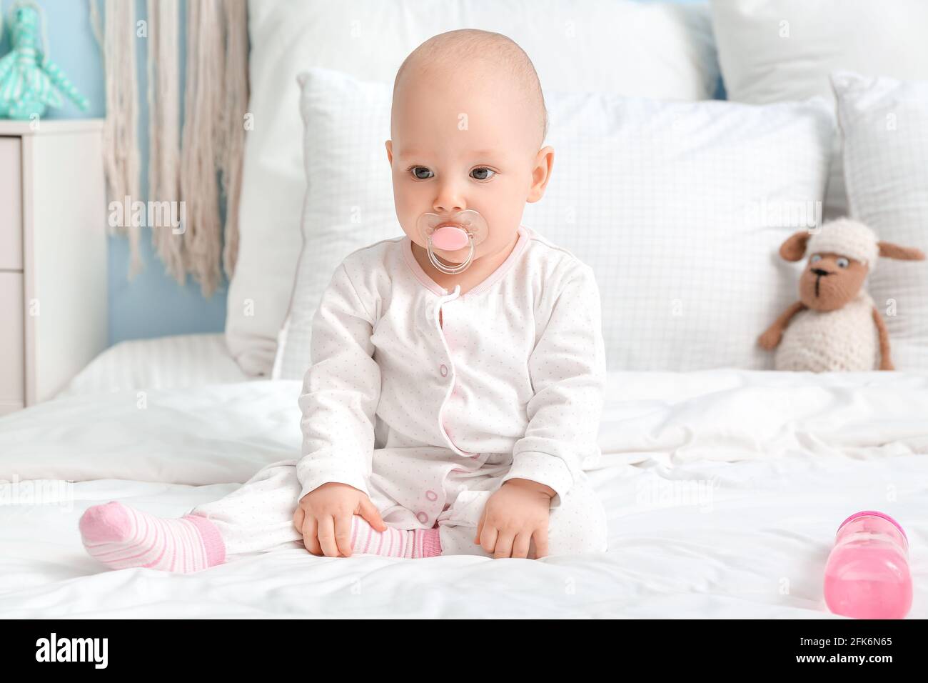 Cute little baby with bottle of water on bed in room Stock Photo - Alamy