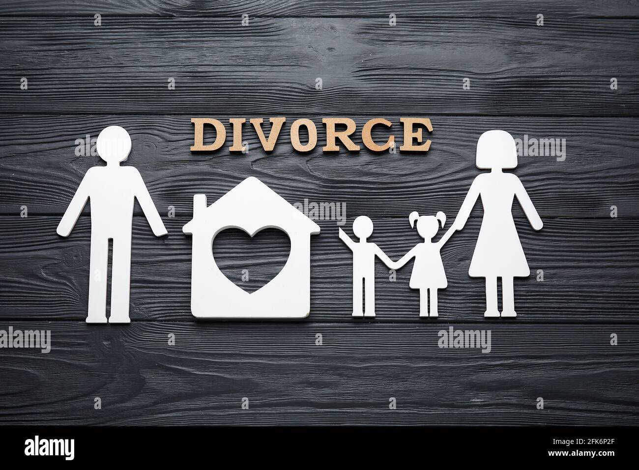 Figures of family with house and word DIVORCE on dark wooden background ...