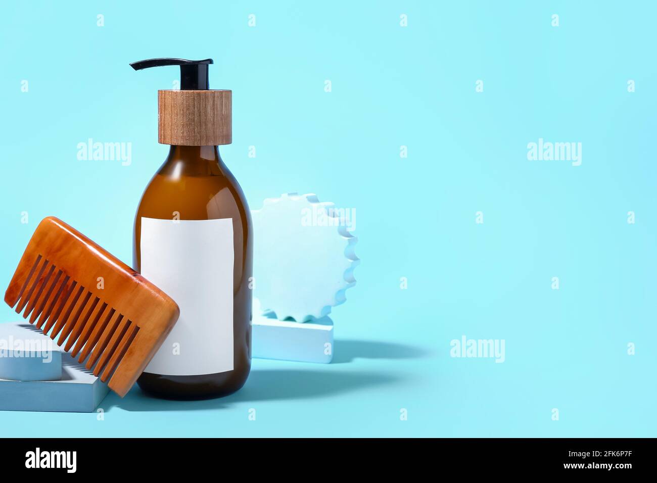 Composition with bottle of natural shampoo and hair comb on color ...