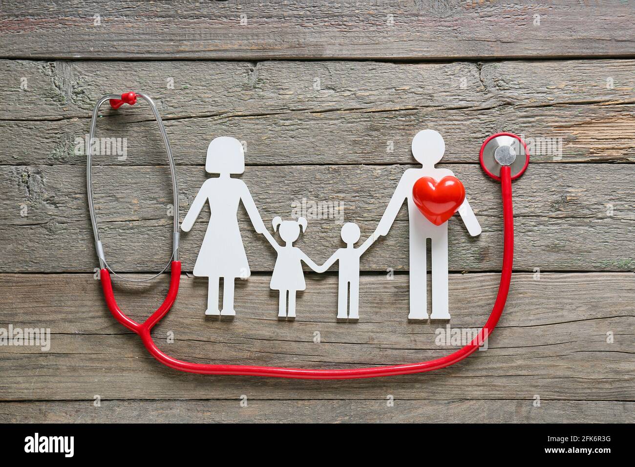 Modern stethoscope with heart and figures of family on wooden ...