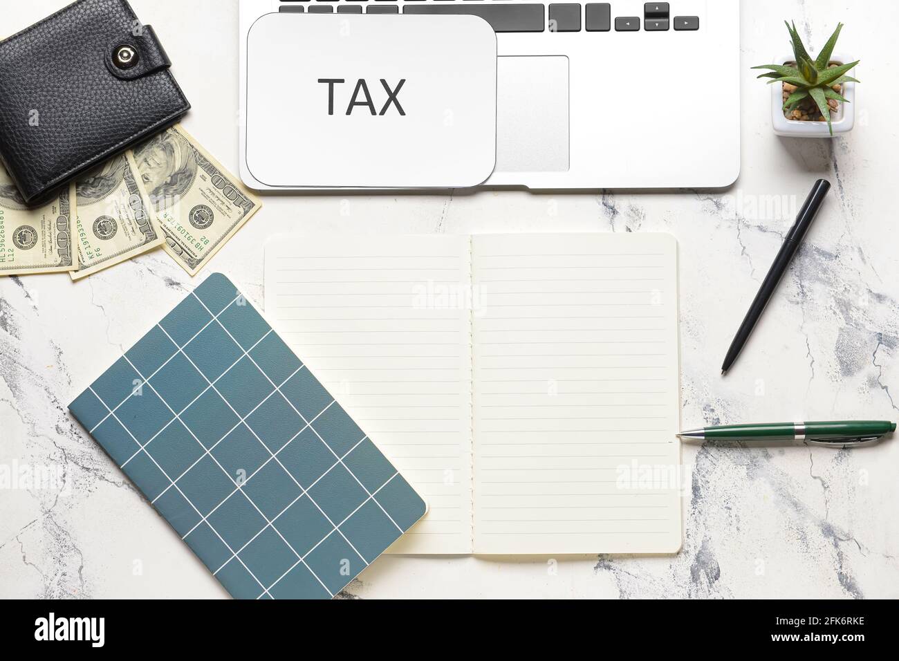 Laptop with wallet, money, notebooks and word TAX on white background ...