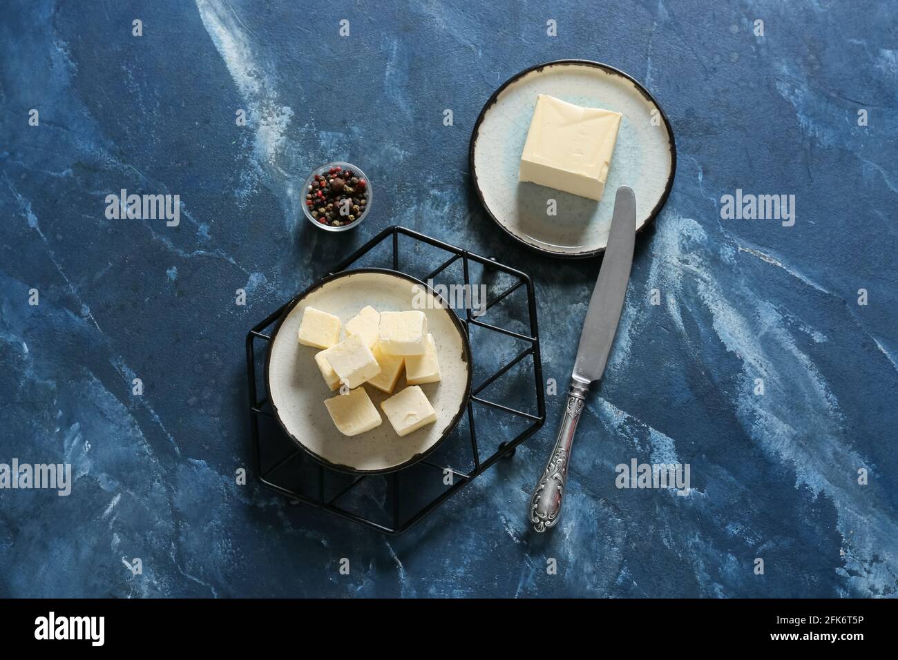 Plates with fresh butter and knife on color background Stock Photo - Alamy
