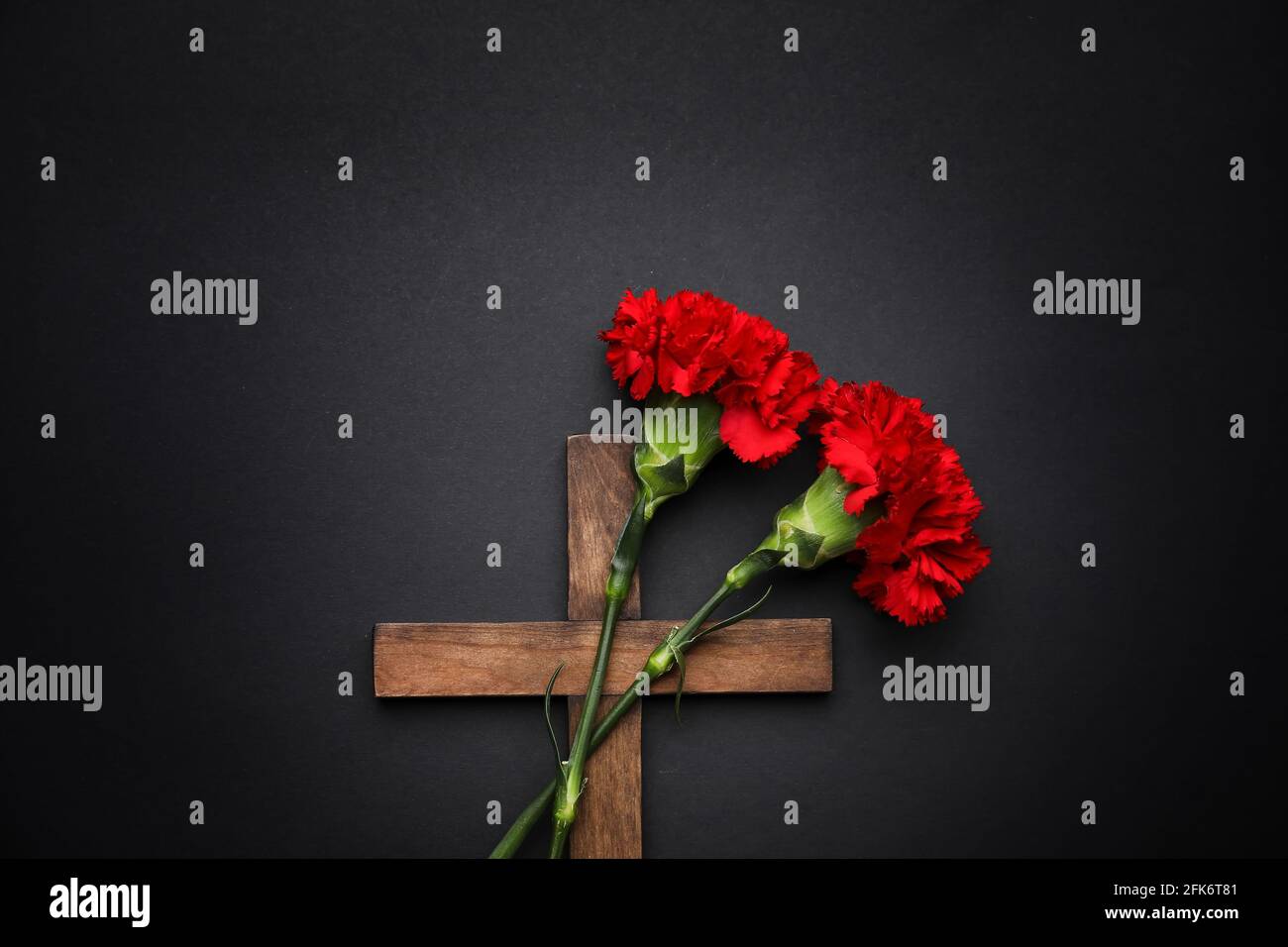 Carnation flowers with wooden cross on dark background Stock Photo - Alamy