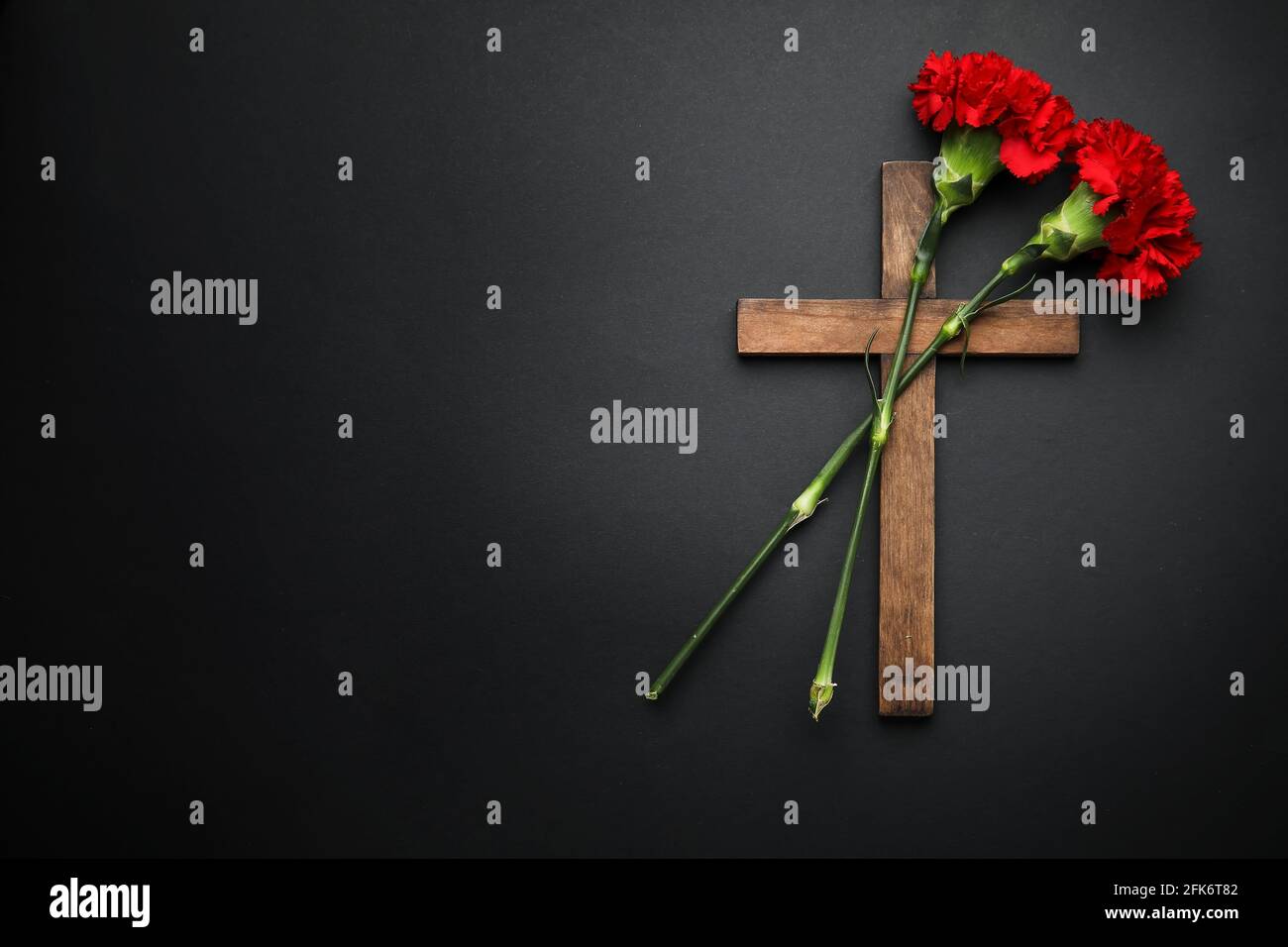 Carnation flowers with wooden cross on dark background Stock Photo - Alamy