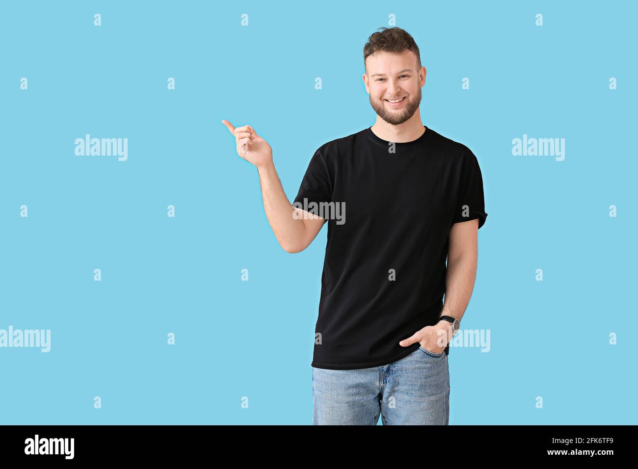 Handsome man pointing at something on color background Stock Photo - Alamy