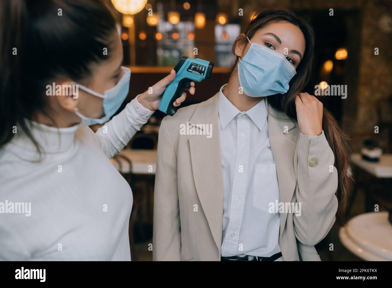Woman measuring body temperature with contactless body thermometer ...