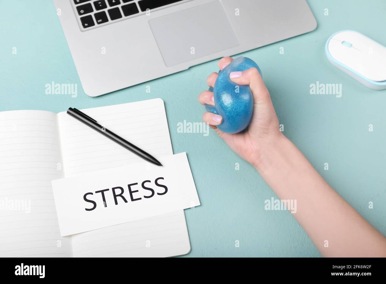 Woman squeezing stress ball while working with laptop in office Stock ...
