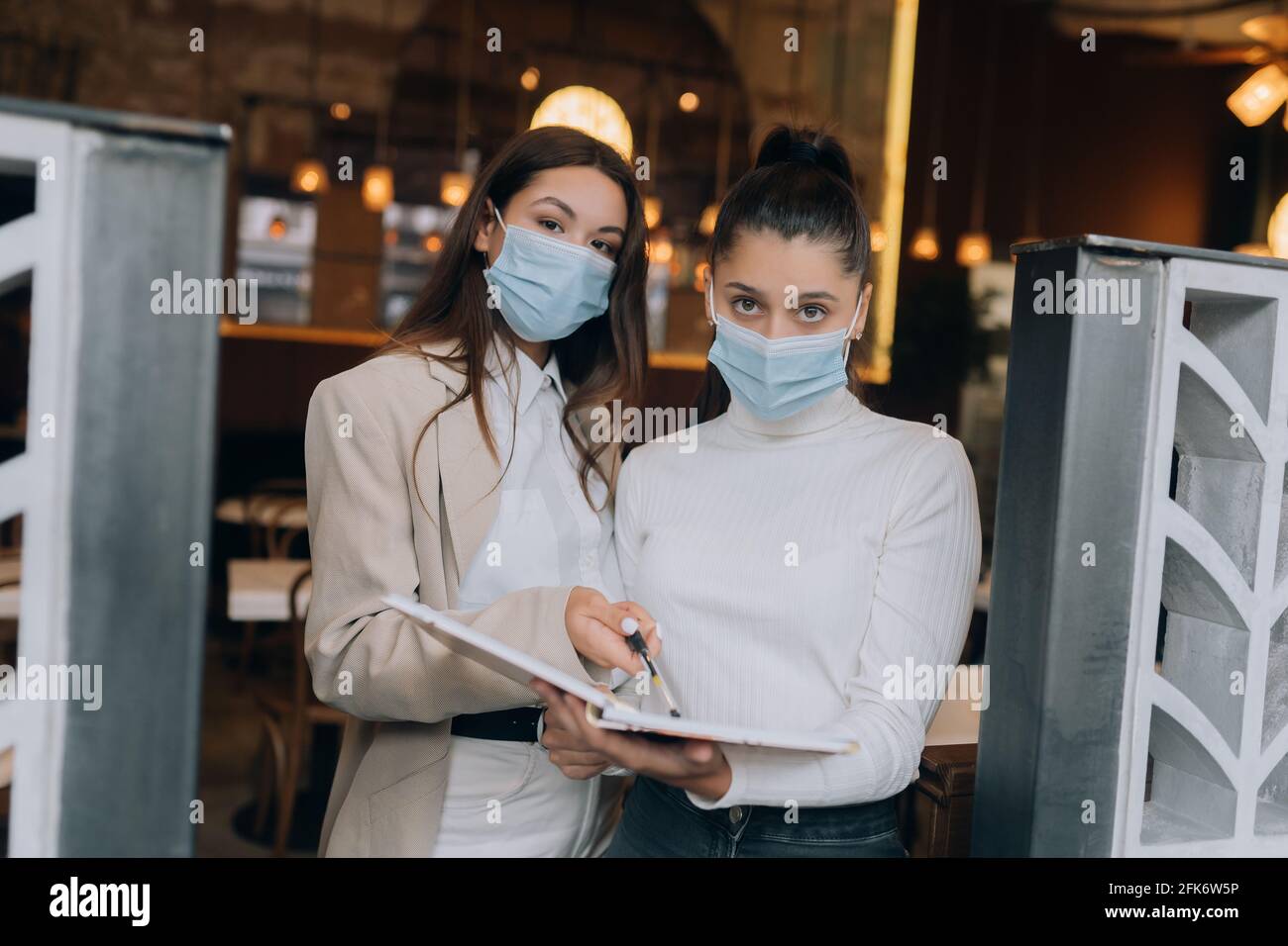 Two girls at the entrance to the building are checking people Stock ...
