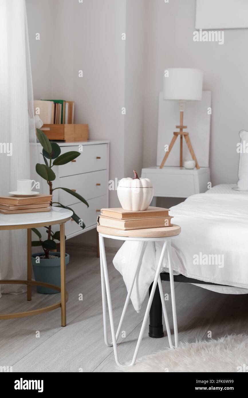 Bedside table with books and decor in interior of room Stock Photo - Alamy
