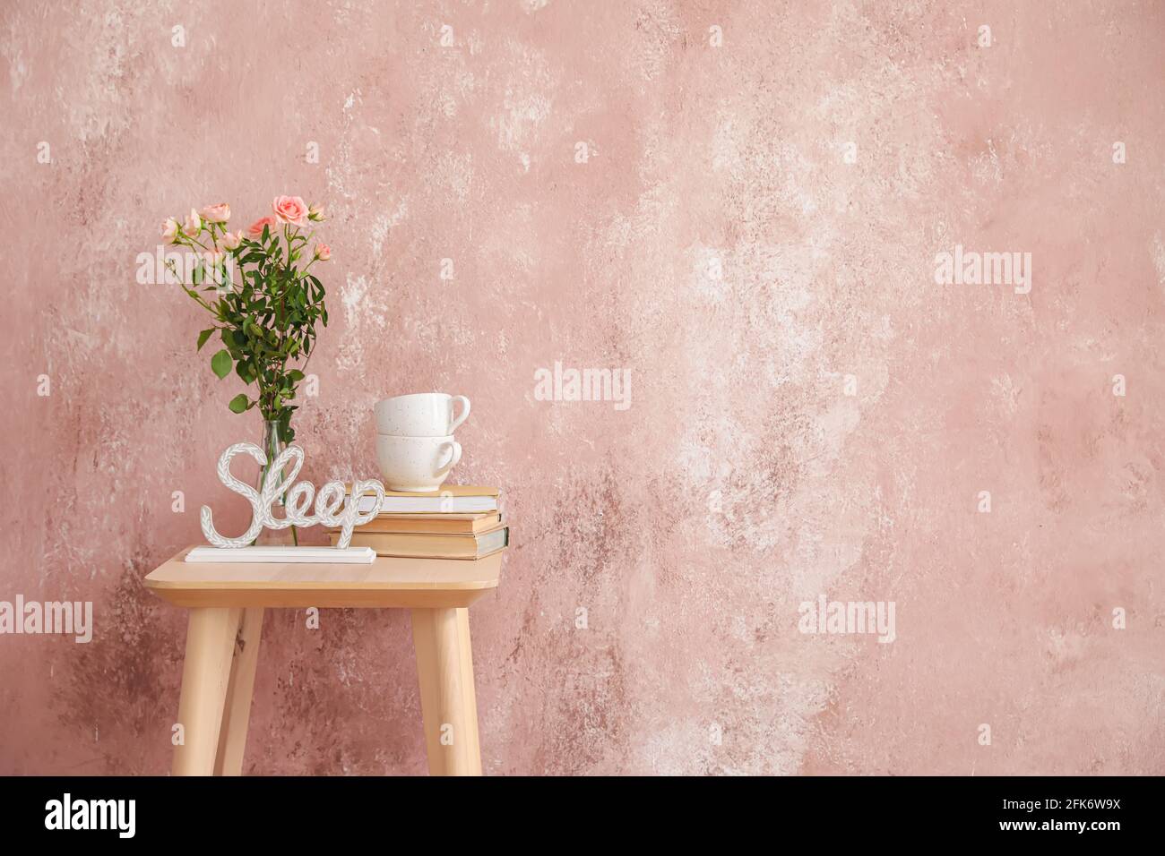 Bedside table with flowers and cups near color wall Stock Photo - Alamy
