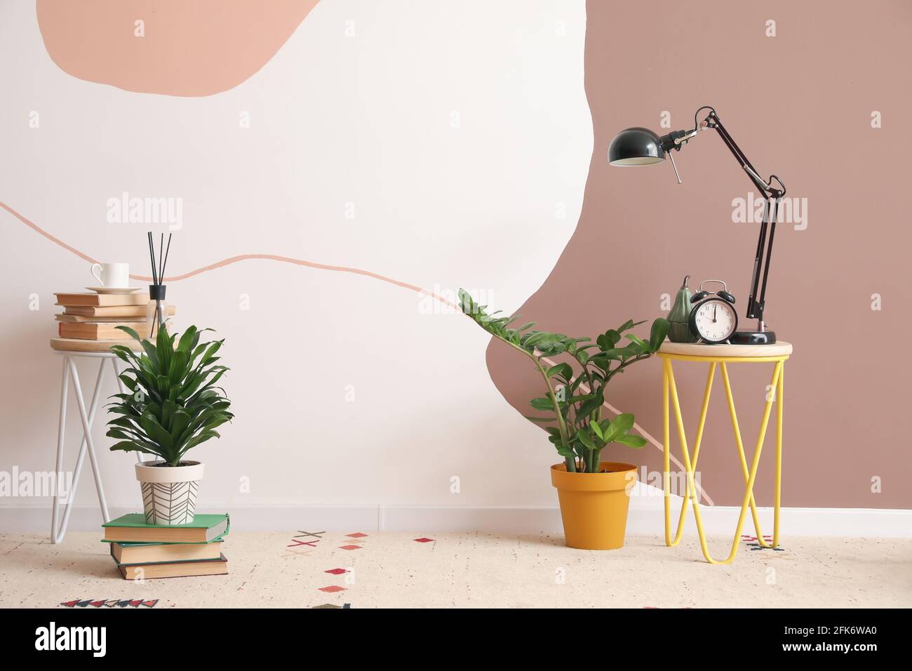 Bedside tables and houseplants near color wall in room Stock Photo - Alamy