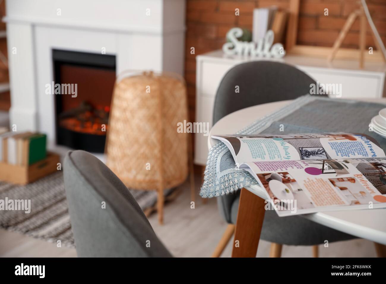 Magazine on table in interior of modern dining room with fireplace ...