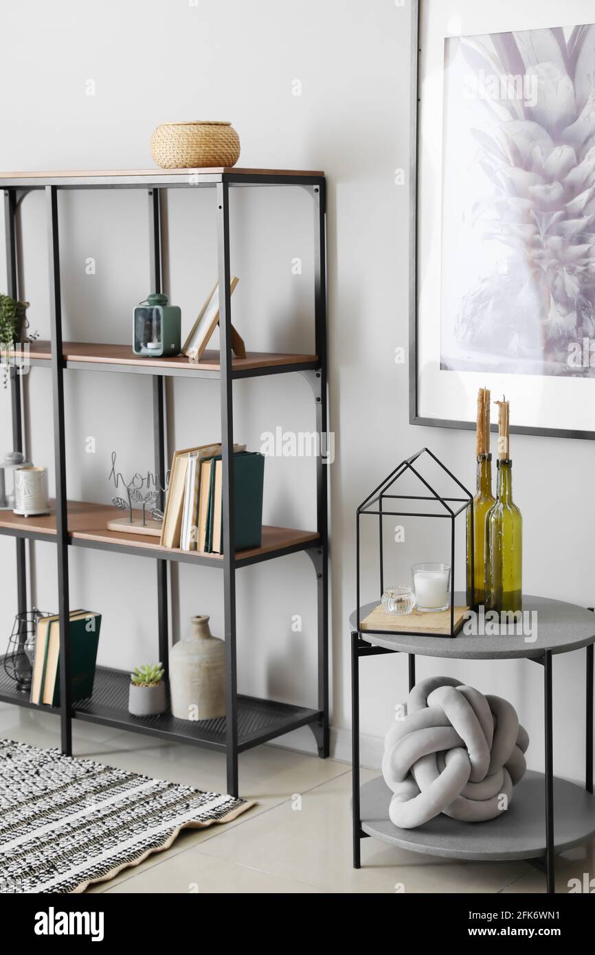 Modern shelf unit with books and table near white wall in room Stock ...