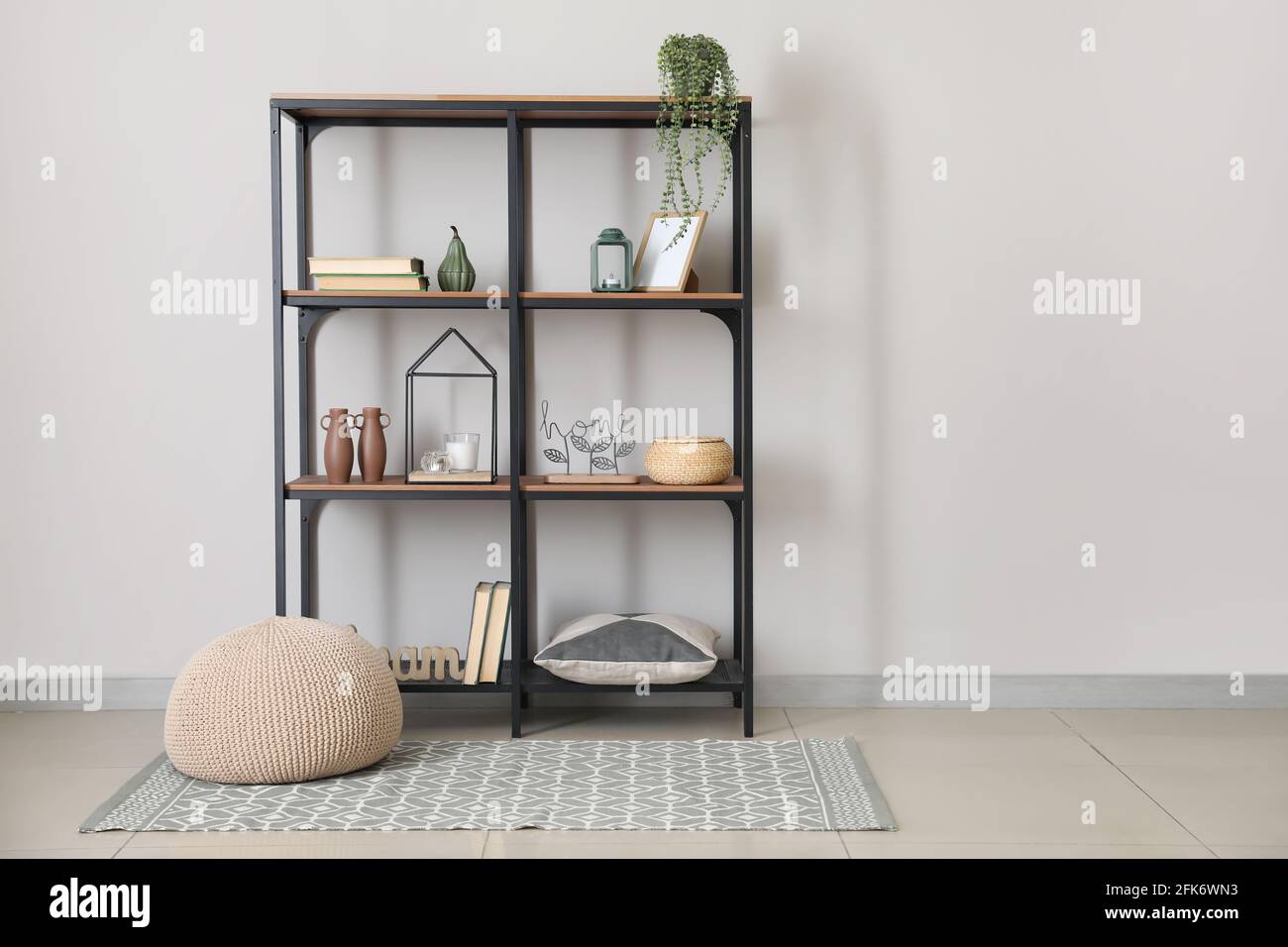 Modern shelf unit with books and decor near white wall in room Stock ...
