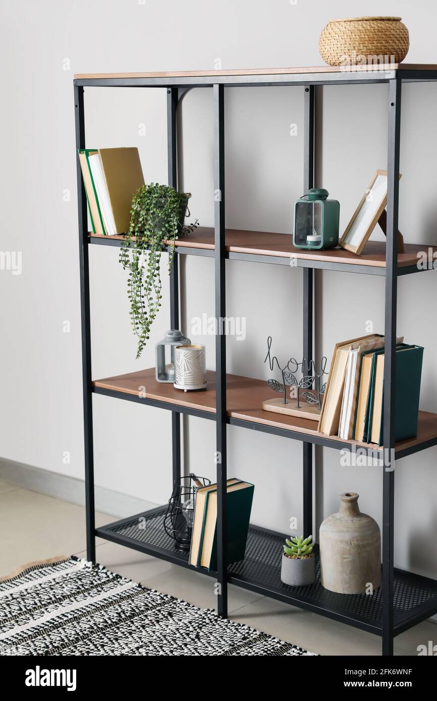 Modern shelf unit with books and decor near white wall in room Stock ...