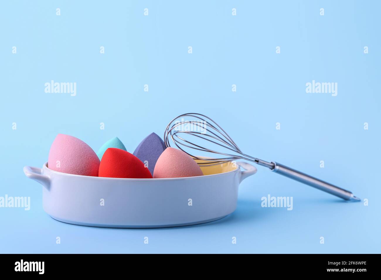 Baking dish with makeup sponges and whisk on color background Stock ...