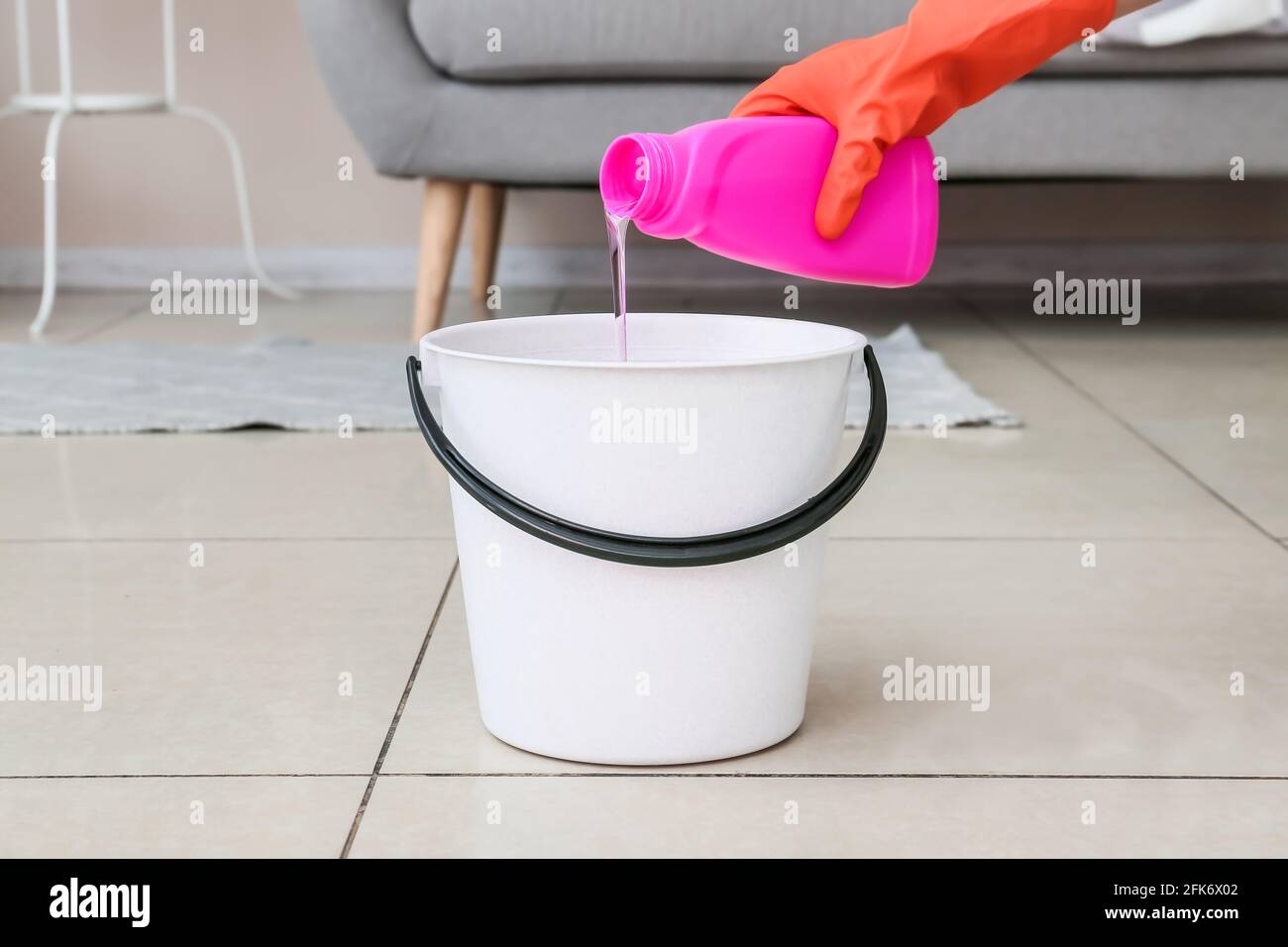 Woman pouring detergent into bucket in room Stock Photo - Alamy