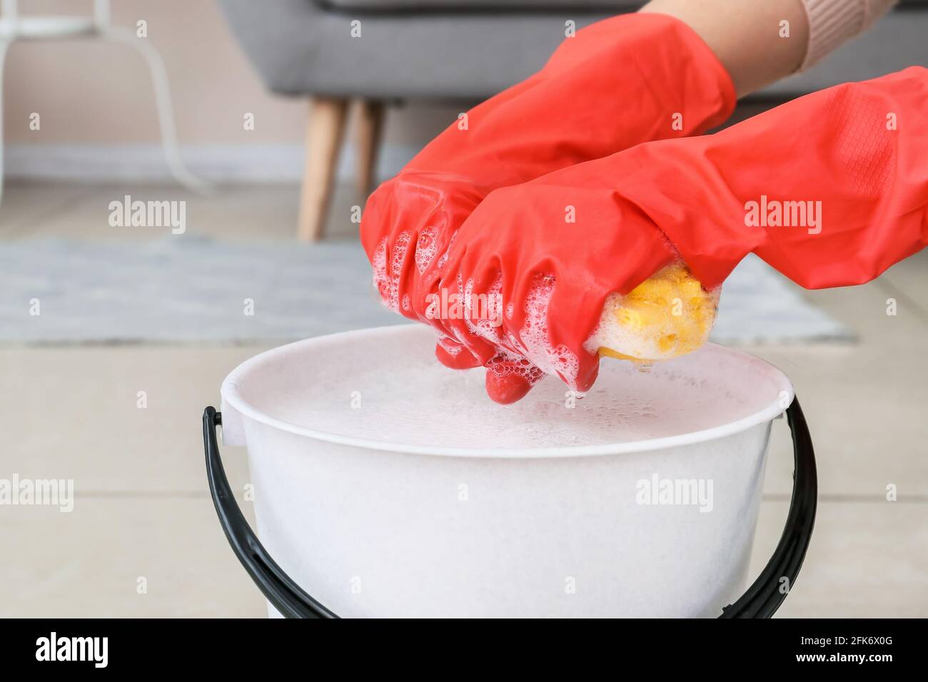Woman squeezing rag into bucket in room Stock Photo - Alamy