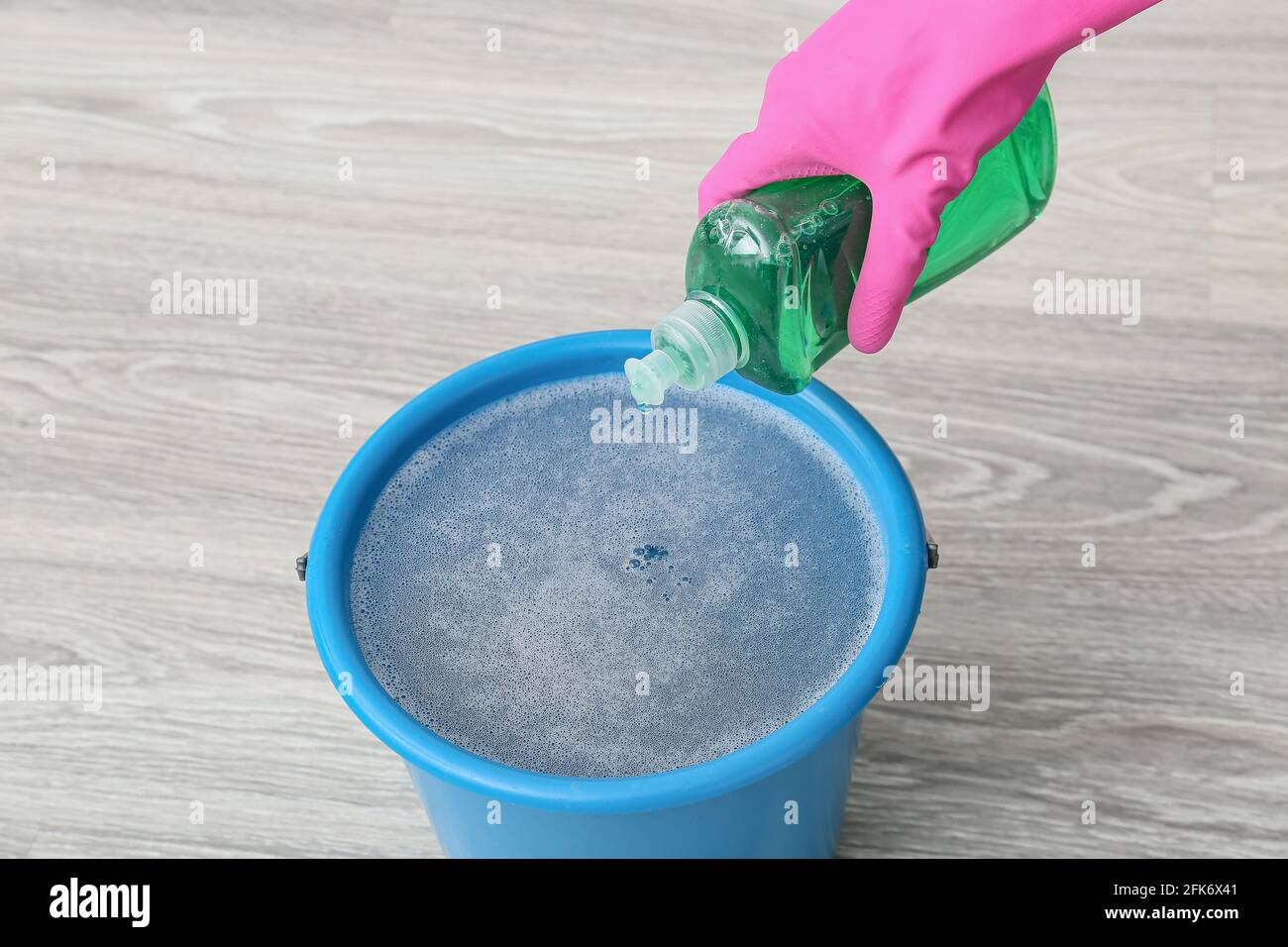 Woman pouring detergent into bucket in room Stock Photo - Alamy