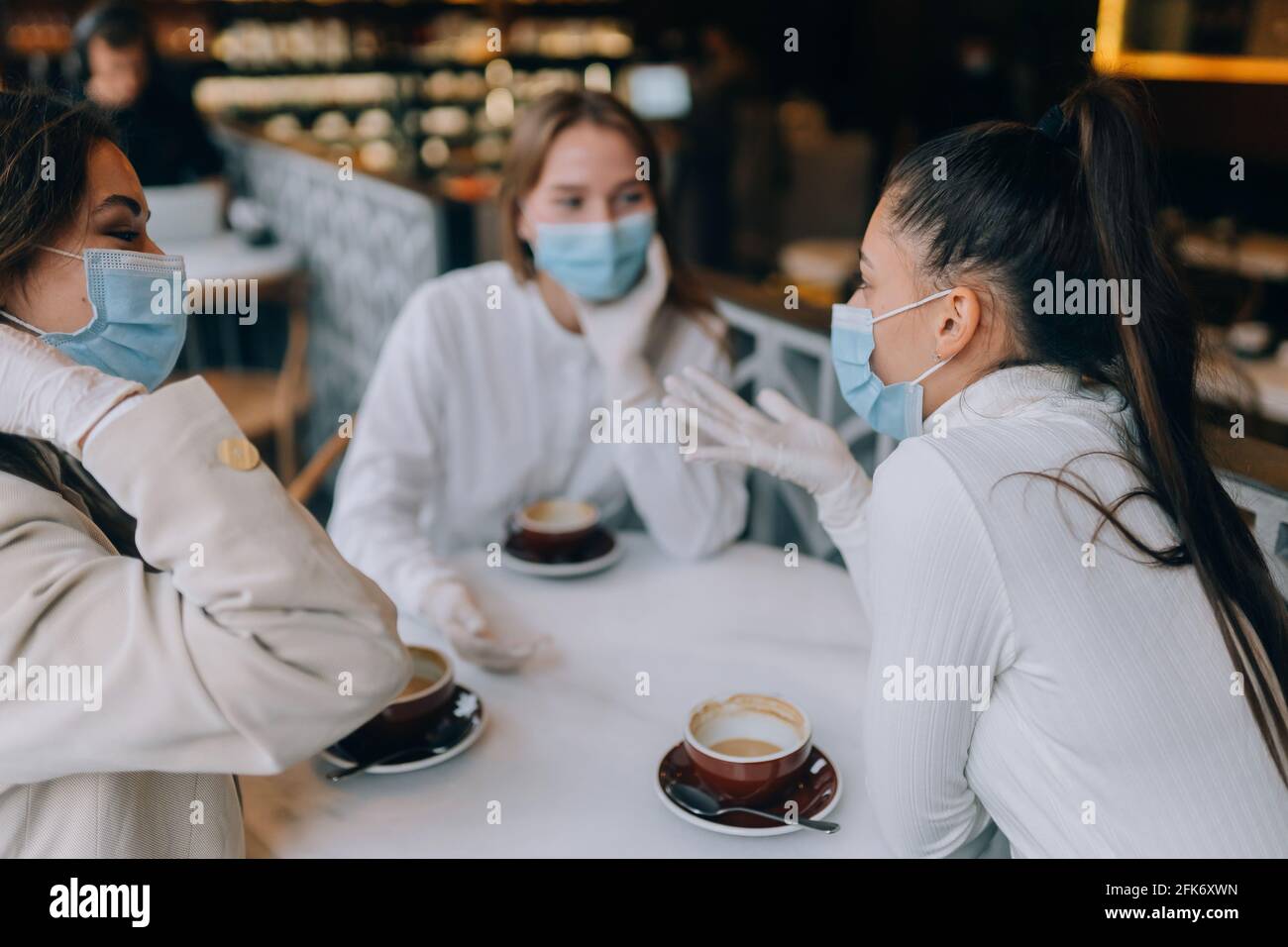Friends girls met in a cafe. Wear medical protective masks Stock Photo ...