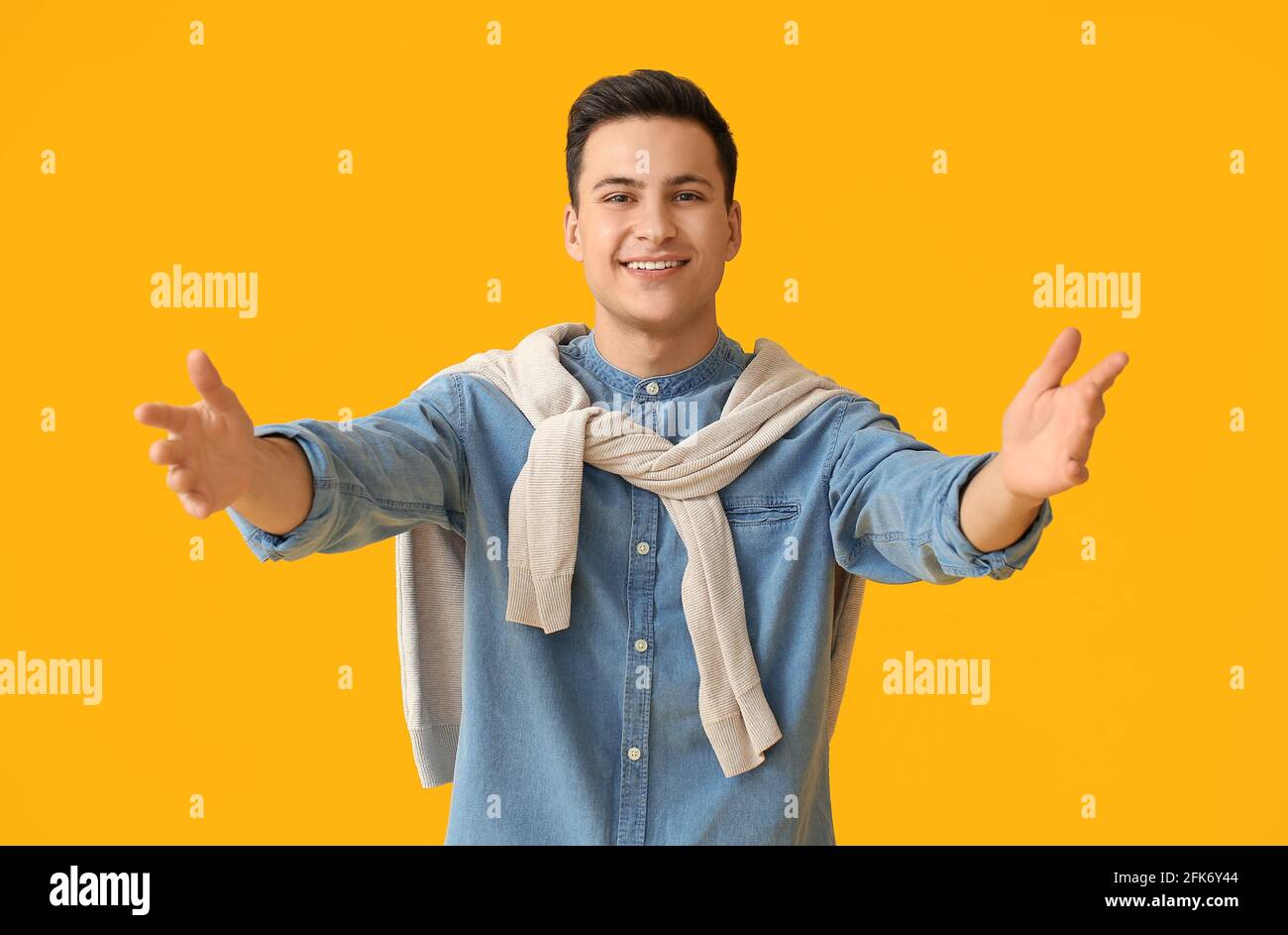 Young man opening arms for hug on color background Stock Photo - Alamy