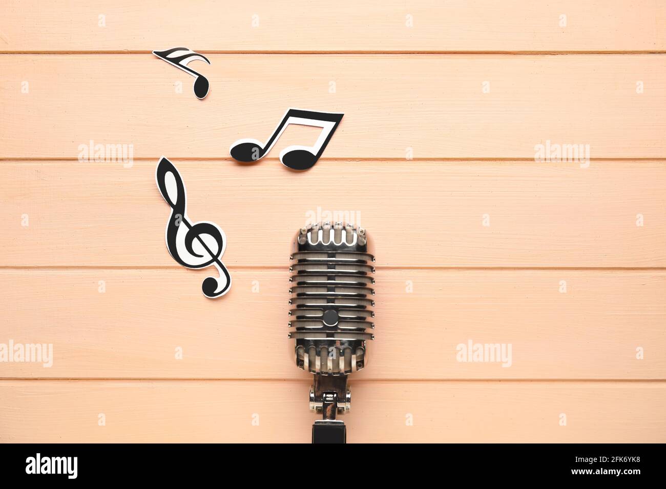 Microphone with music notes on color wooden background Stock Photo - Alamy