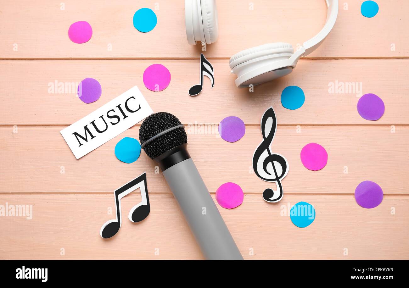 Microphone with headphones, music notes and confetti on color wooden ...