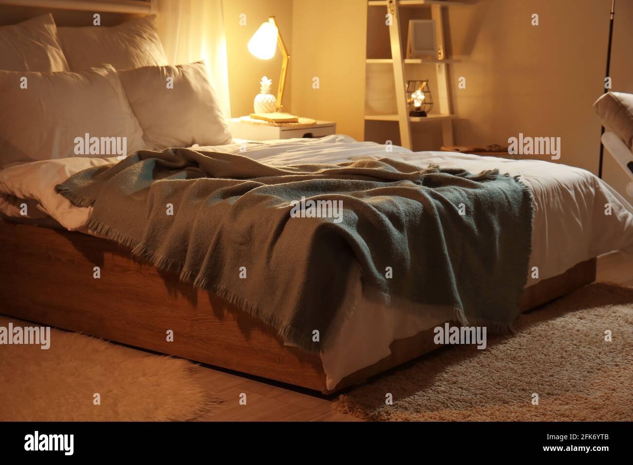 Big comfortable bed in room at night Stock Photo - Alamy